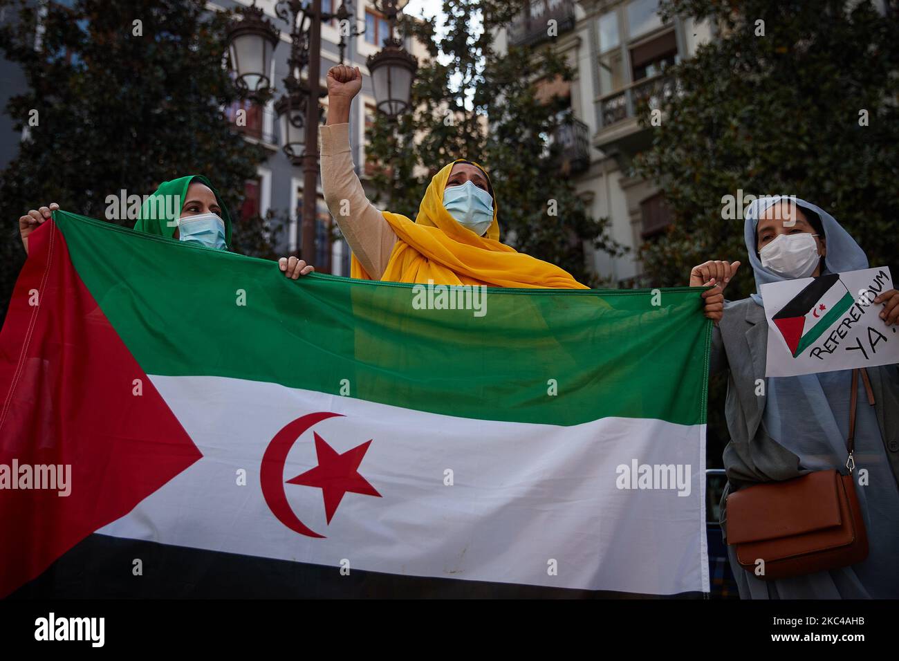 Women wearing face mask carrying a Saharan flag and dressed in Malahfas ...