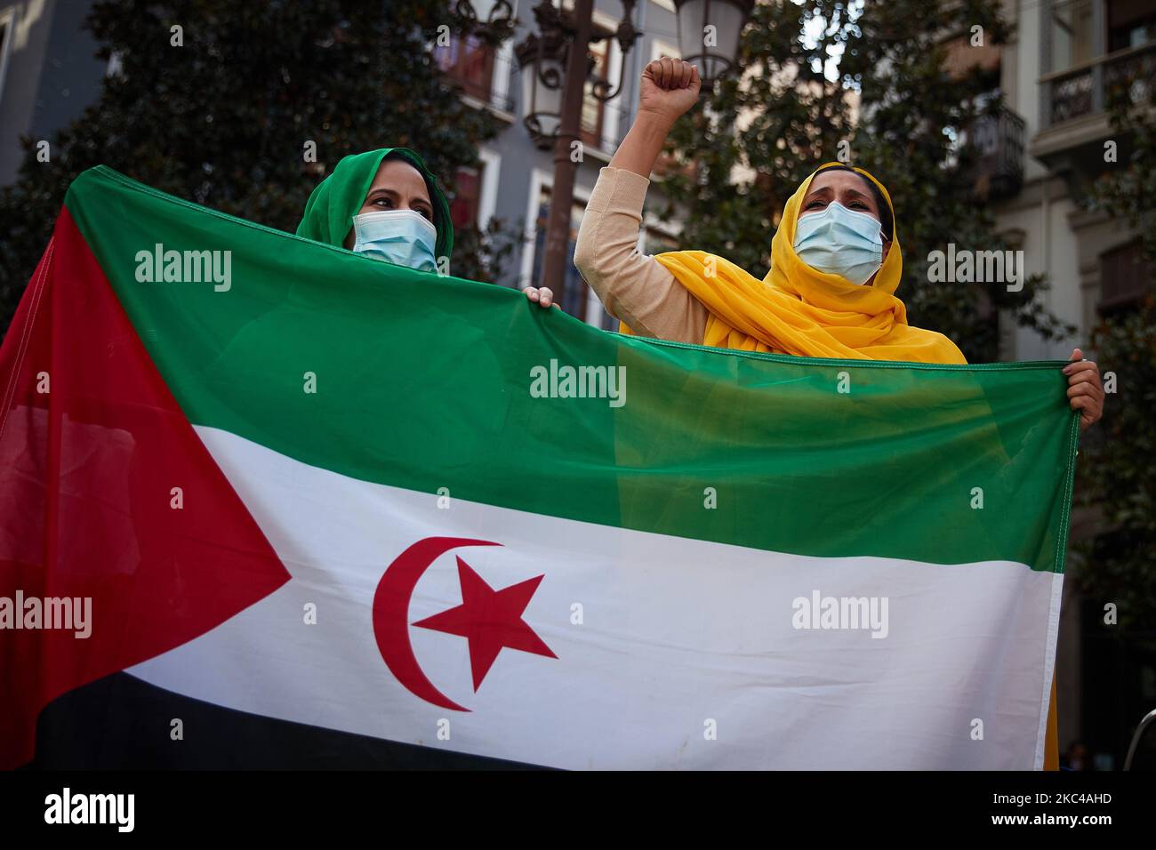 Women wearing face mask carrying a Saharan flag and dressed in Malahfas ...