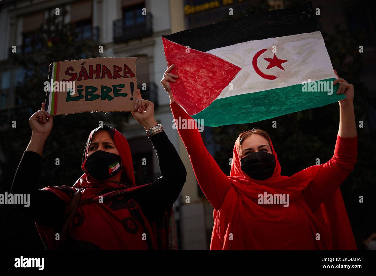 Women wearing face mask, carrying a Saharan flag and a placard that ...
