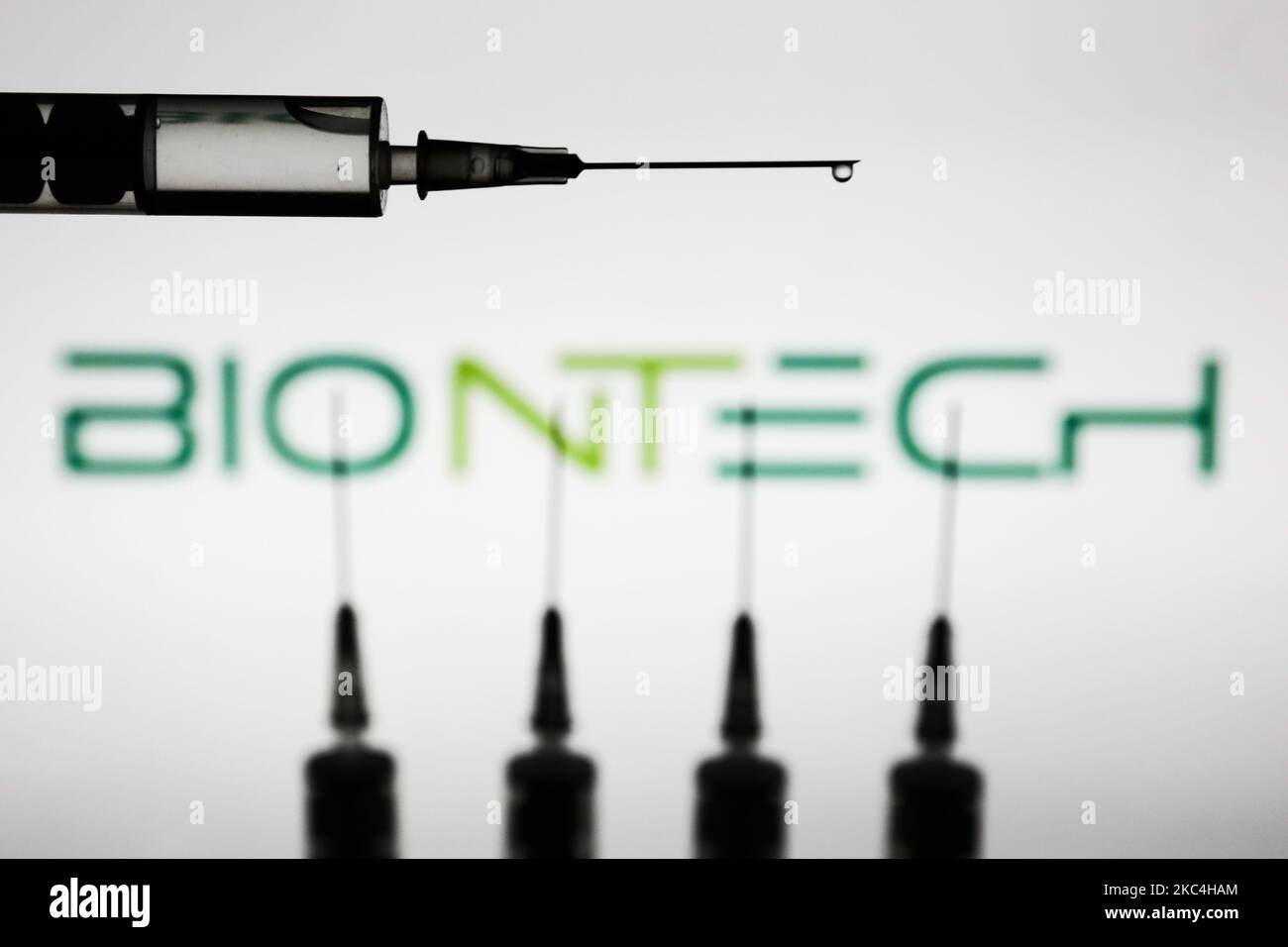 Medical syringes are seen with BioNTech logo displayed on a screen in ...