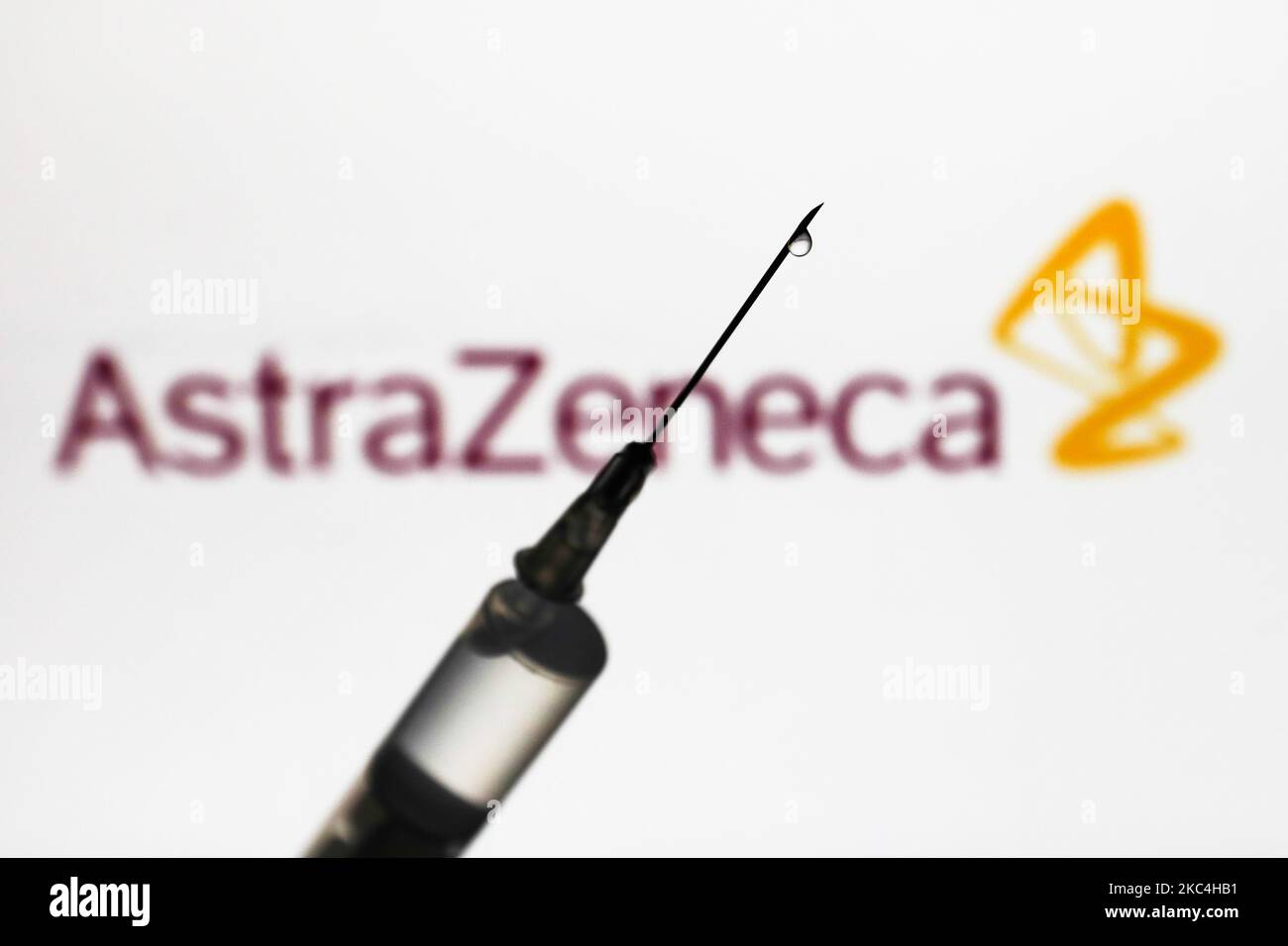 Medical syringe is seen with AstraZeneca logo displayed on a screen in ...