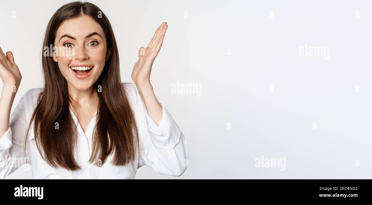 Enthusiastic young woman celebrating, smiling and raising hands up in ...