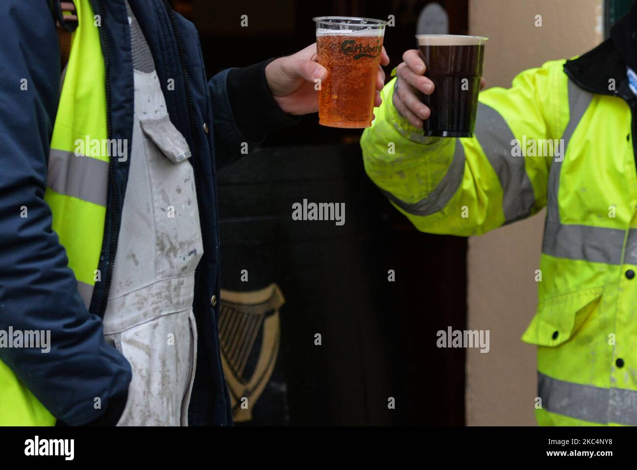 People enjoy pints of beer served in a plastic cups outside a pub in ...