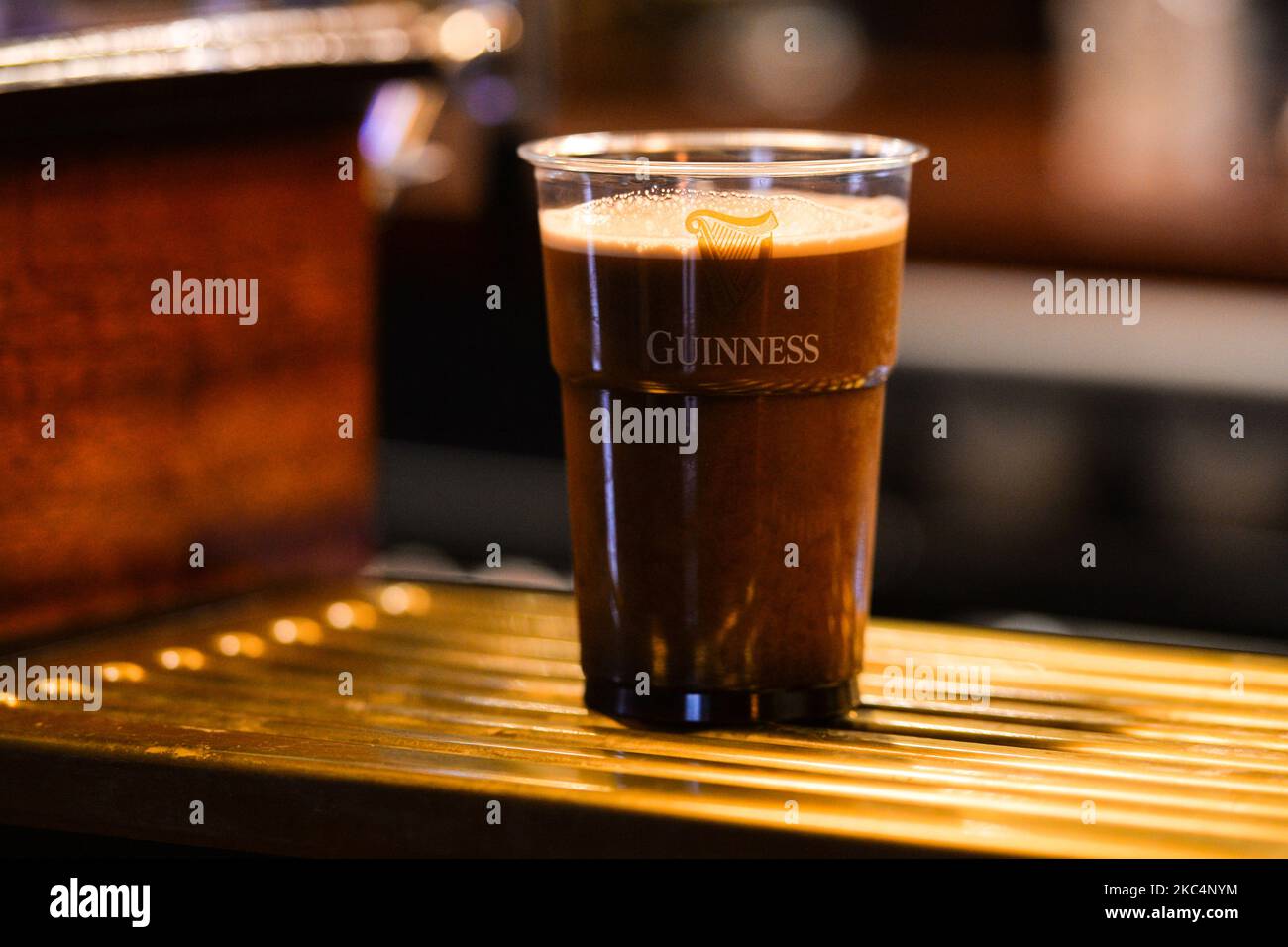 A pint of Guinness just pulled in a plastic cup inside a pub in Dublin ...
