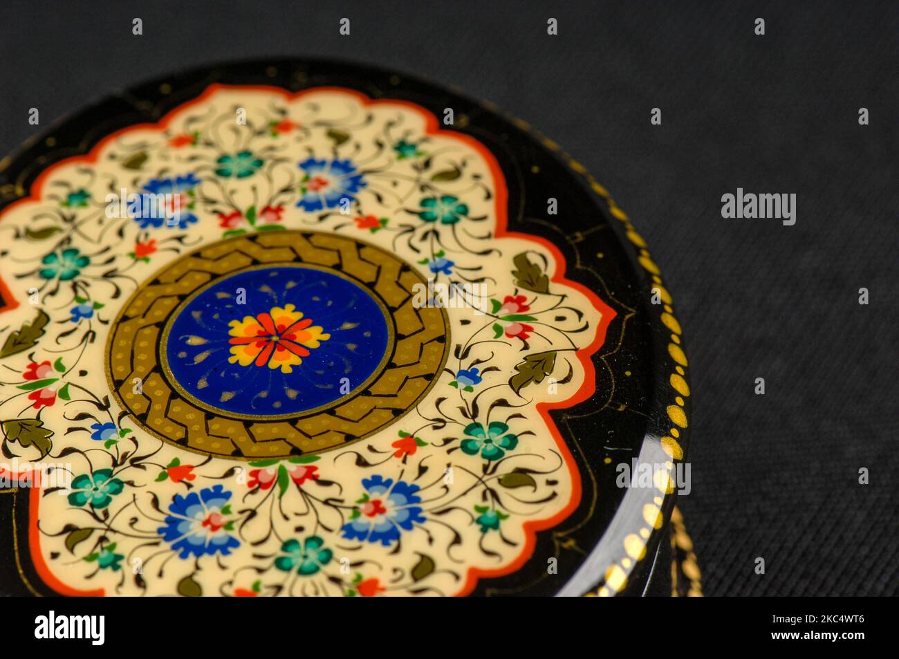 A closeup of a round casket with an artistic painting on a black ...