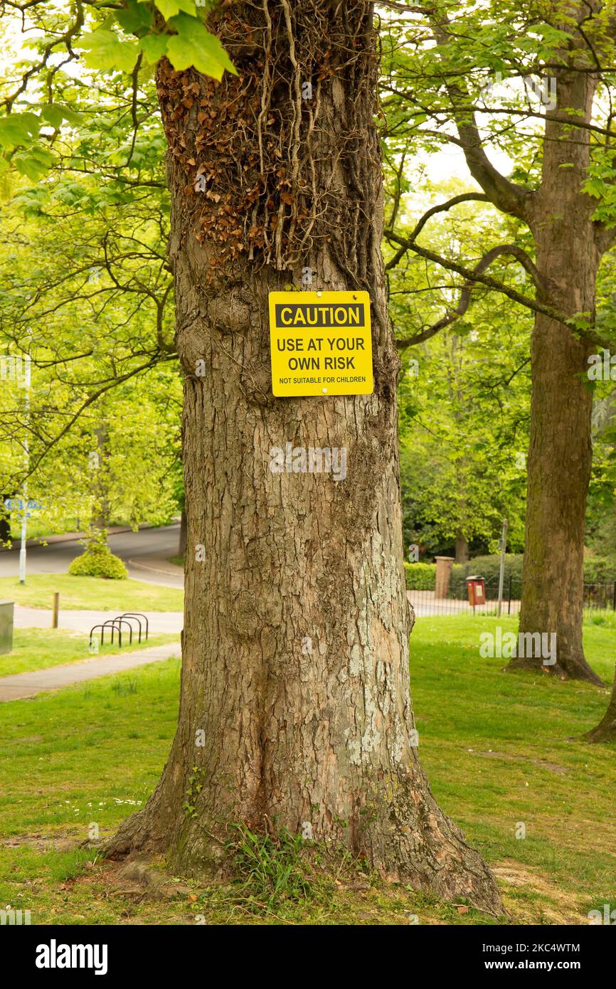 A vertical shot of bright yellow warning sign on tree saying Caution ...