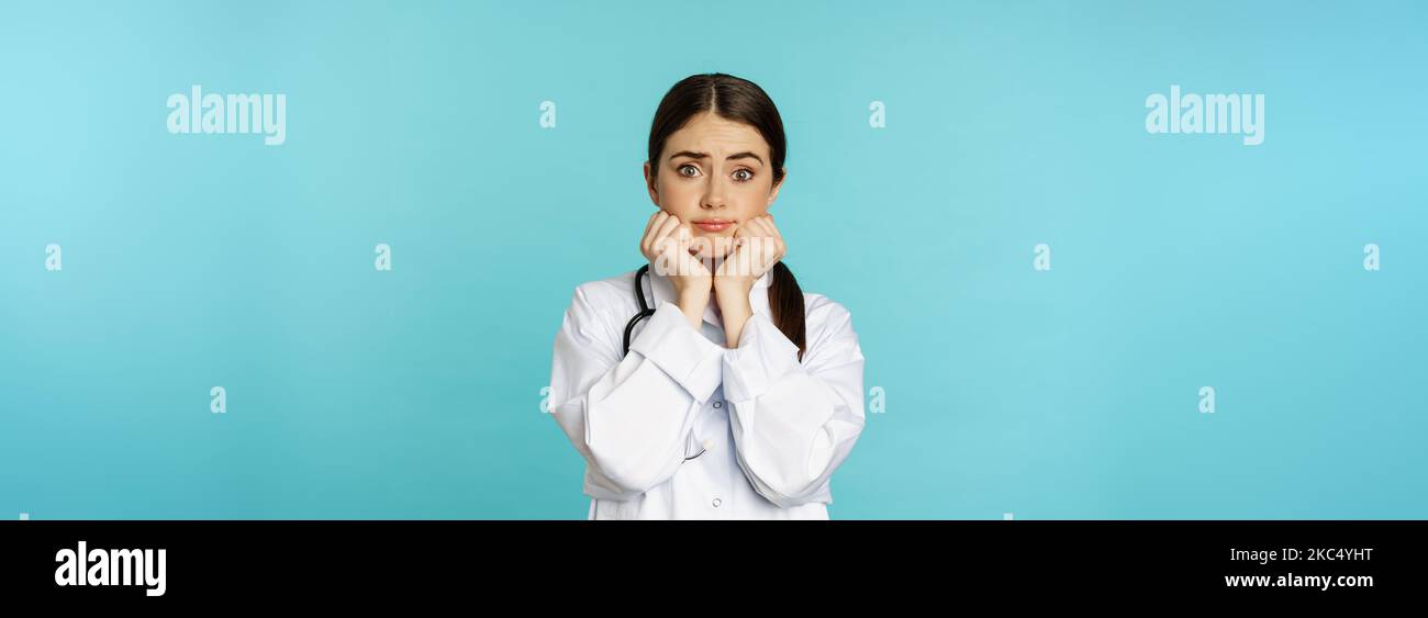 Scared and worried woman doctor in white coat, looking anxious and ...