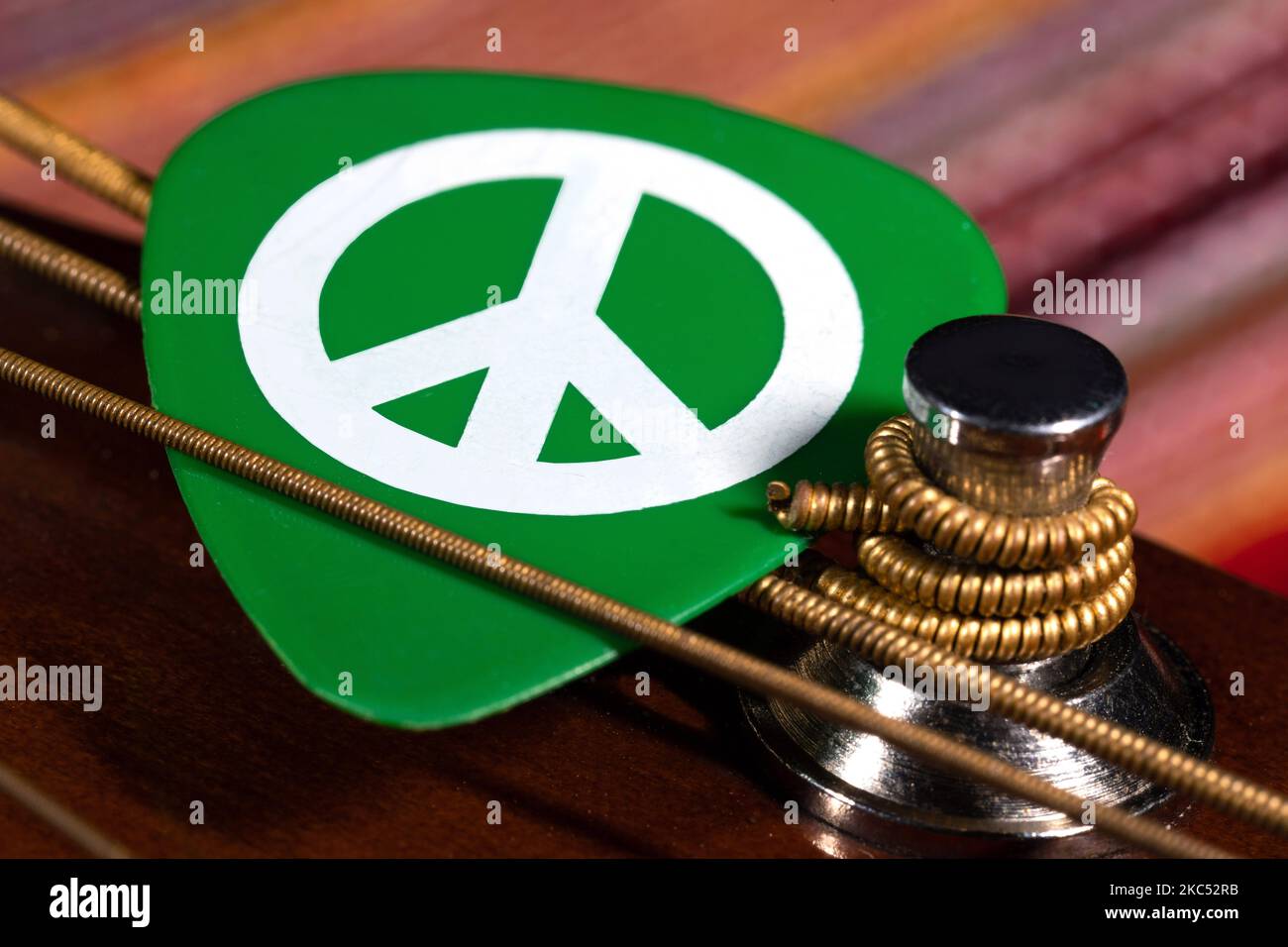 A macro shot of a guitar plectrum with the peace sign on it in between ...
