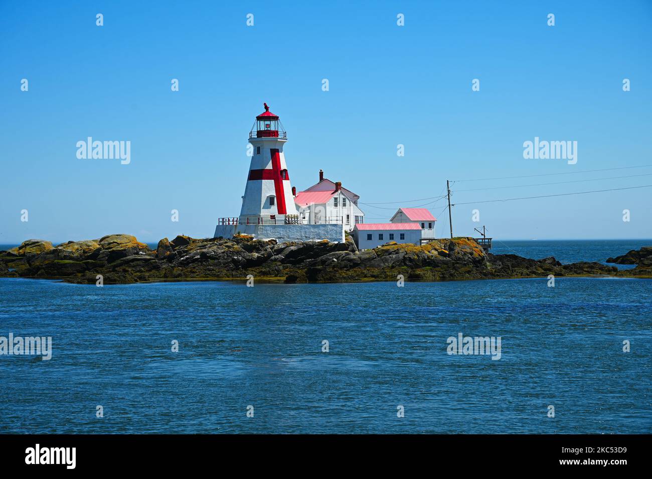 A lighthouse with a red roof on a small island Stock Photo - Alamy