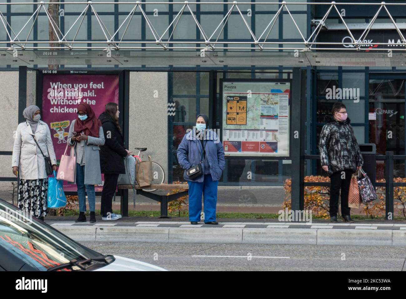 Group of people waiting at the bus stop, wearing facemasks. Daily life ...