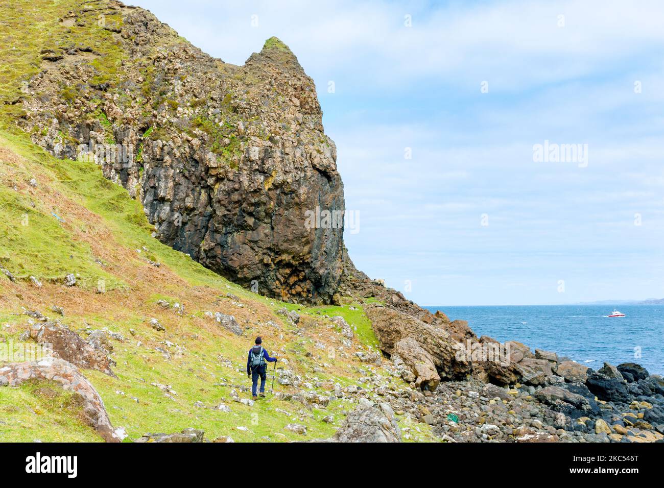 A walker on the coastal track below Ben Tianavaig, near Portree, Isle ...