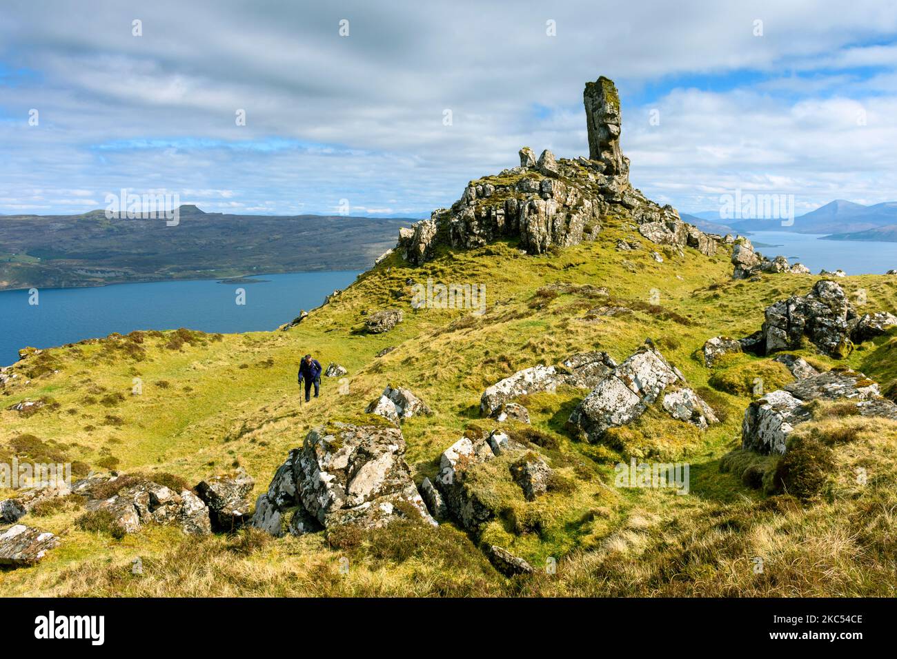 A walker below a rock pinnacle on the eastern slopes of Ben Tianavaig, near Portree, Isle of ...