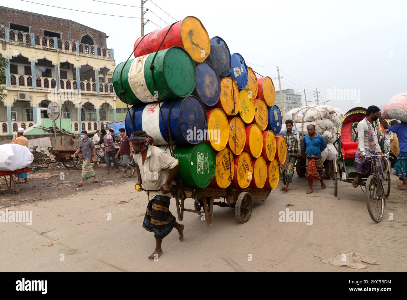 Bangladeshi worker carries empty drum by the wheelbarrow amid the COVID ...