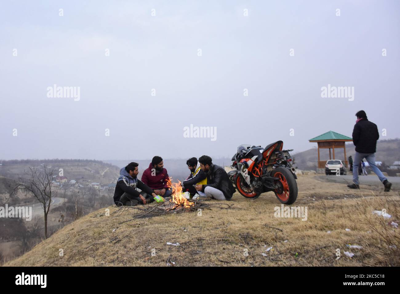 Kashmiri bikers sit around bonfire on the hills of in Chrar area of Budgam District, Indian ...
