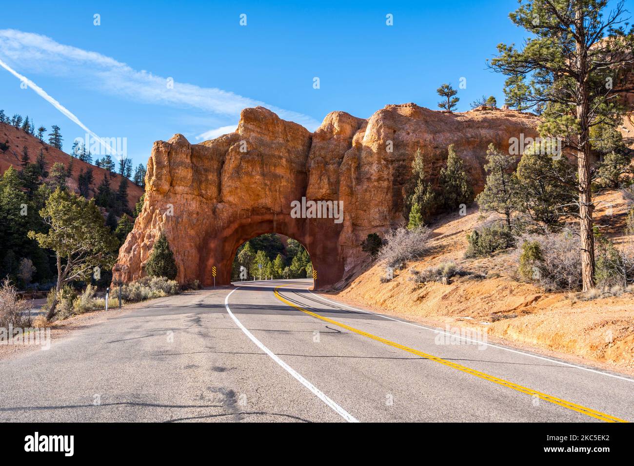 A beautiful view of a road in Utah with an arch in the middle of ...