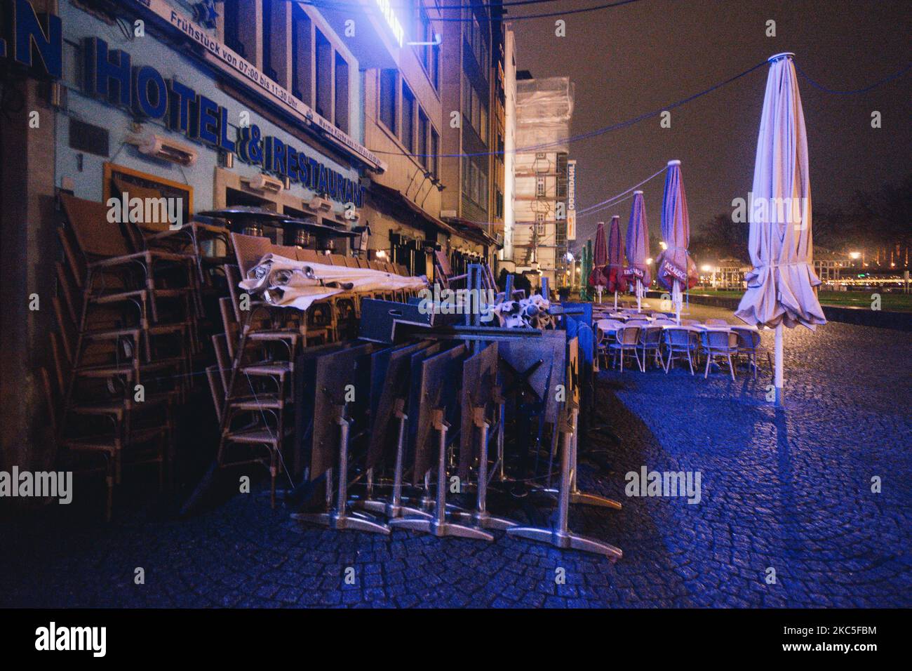 chairs and tables are stacked in front of a closing cafe in the city ...
