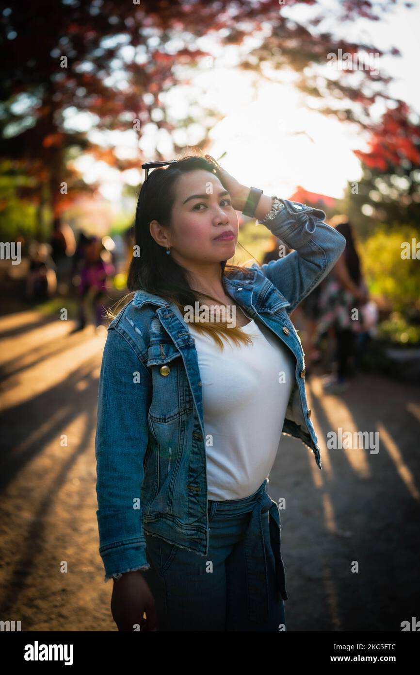 A vertical shot of a young cute Filipino woman posing outdoor in a park ...