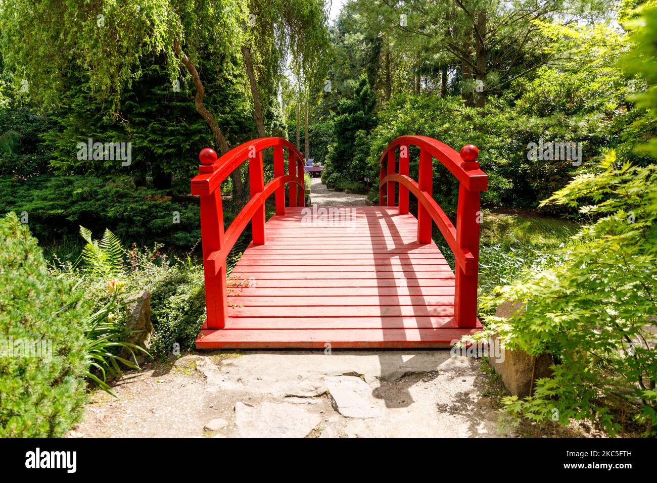Japanese style red bridge in a naturalistic garden Stock Photo - Alamy