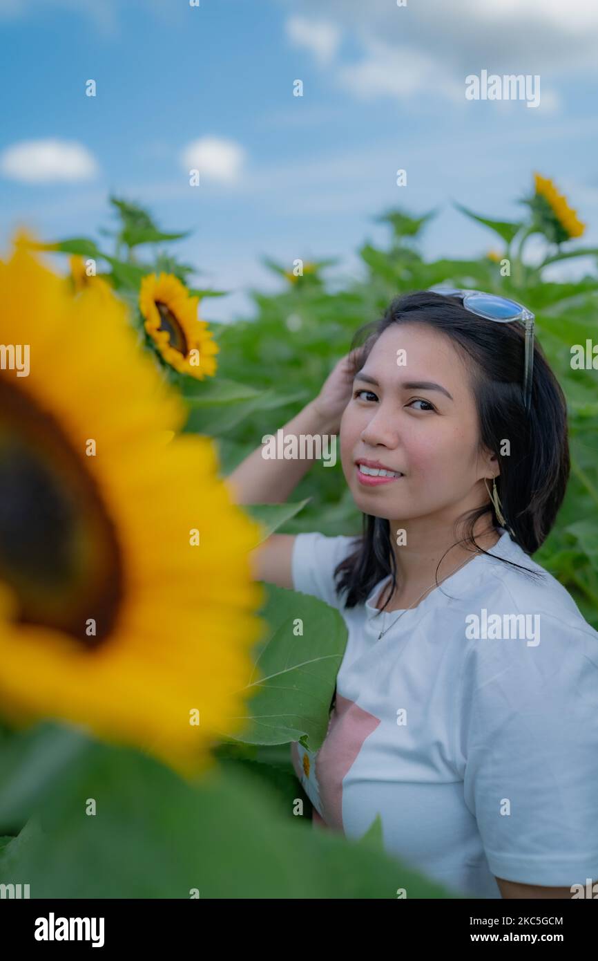 A vertical shot of a young South Asian female posing in the sunflower ...