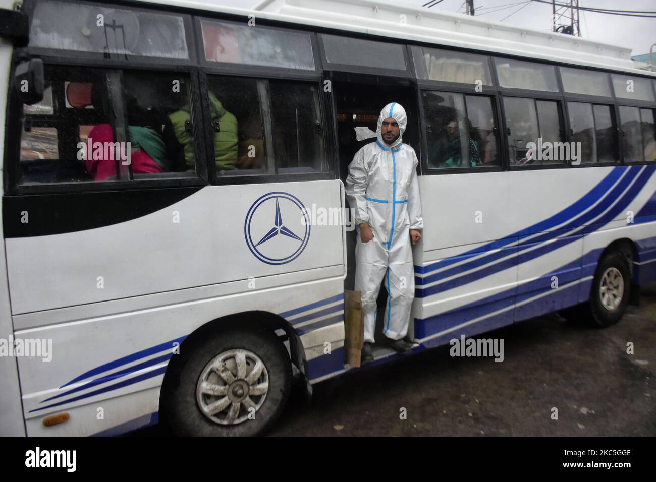 A bus conductor wears a PPE suit on a cold winter day as it rains in ...