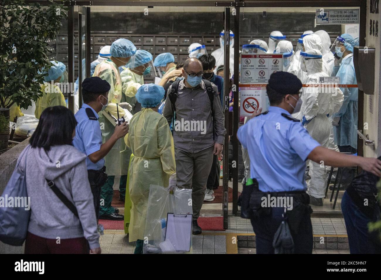 Workers wearing PPE are seen escorting people out a Residential ...