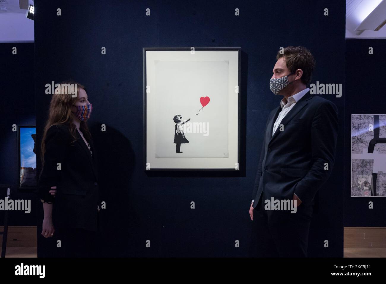 (EDITORIAL USE ONLY) Staff members pose with Banksy's (born 1975) Girl ...