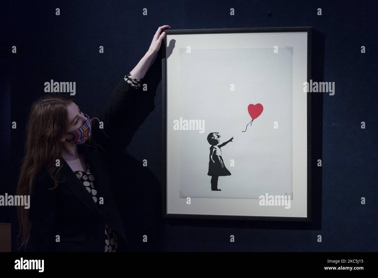 (EDITORIAL USE ONLY) A staff member poses with Banksy's (born 1975 ...