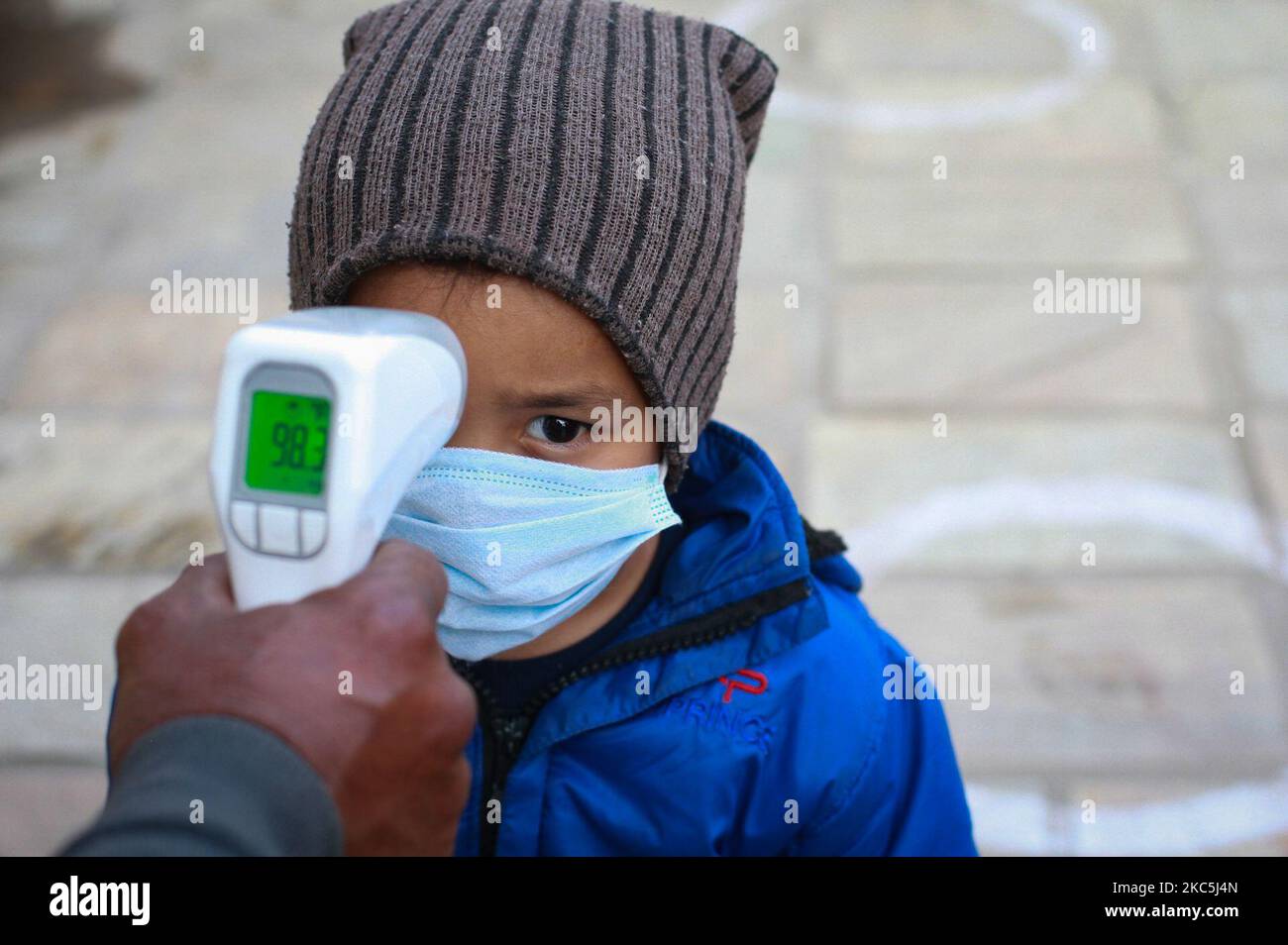 A staff member wearing personal protective equipment measures body ...