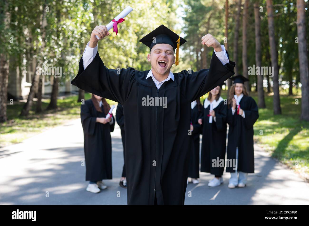 Happy young caucasian man celebrating graduation. Crowd of students ...