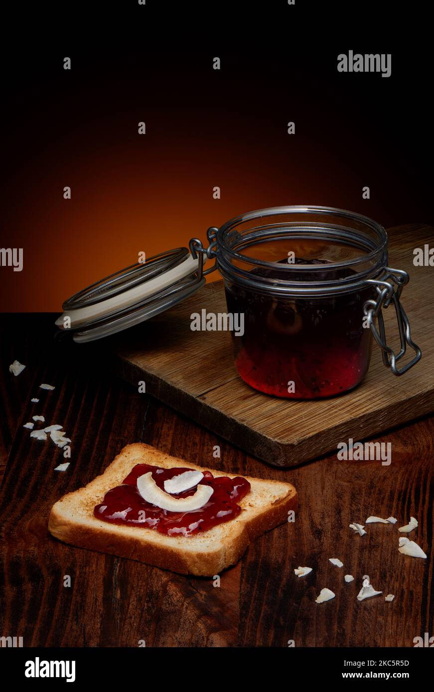 Crispy slice of toast with coconut flakes and jar of strawberry jam on ...