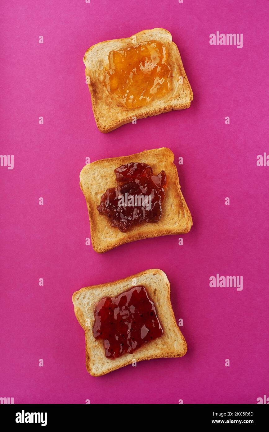 Three crispy slices of toast with strawberry, apricot and fig jam on ...