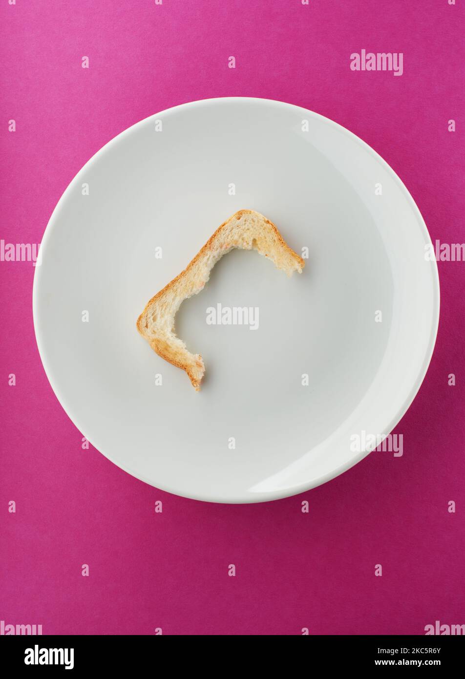 Leftover toast crust on white plate and bright pink background Stock ...