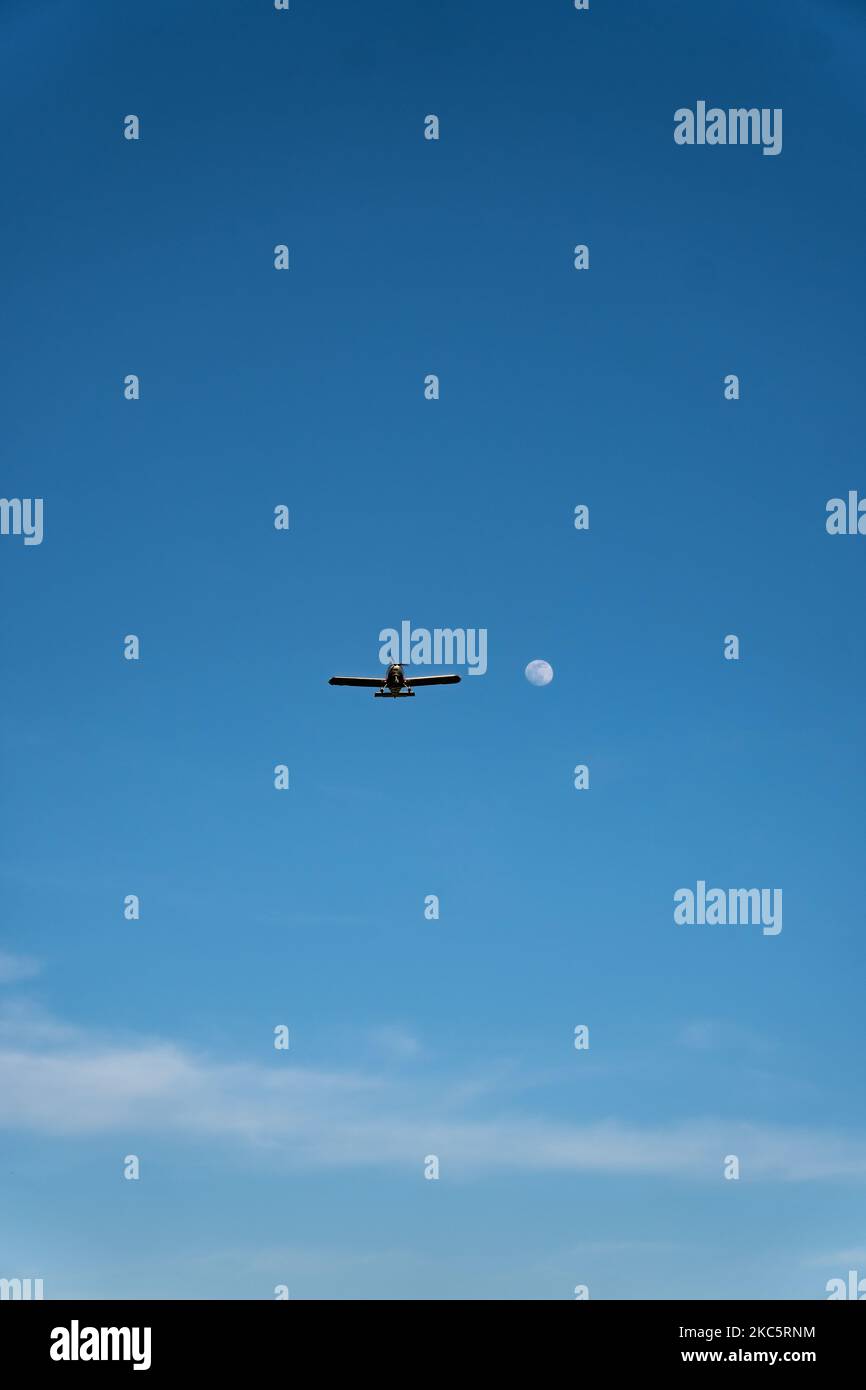 The red airplane flying through the blue sky with a white contrail ...