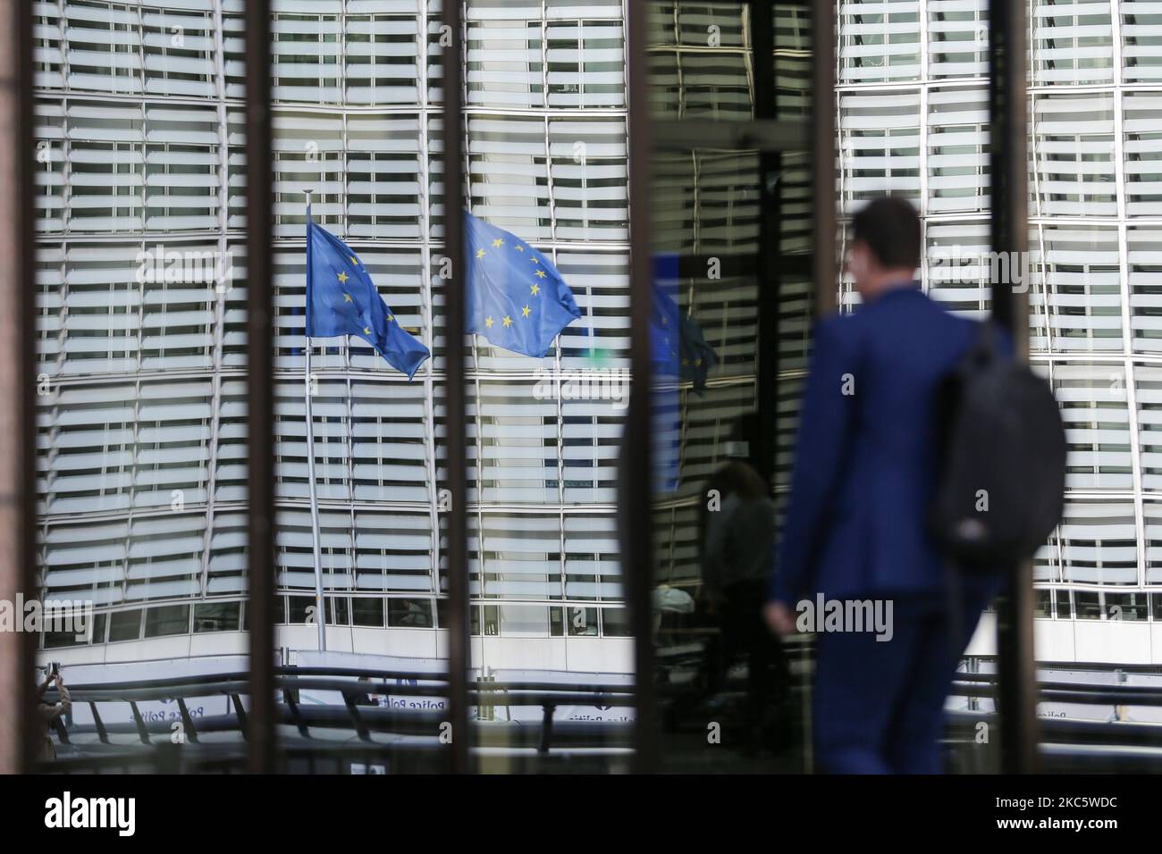Reflection of European flags while a man enters a building. Flags of ...