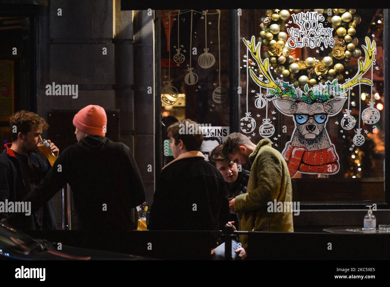 People having a drink outside a pub, with Christmas decorations in the ...