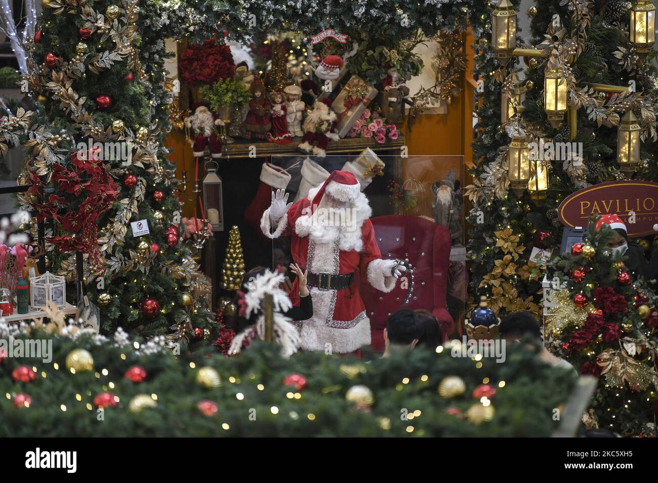 Santa Claus behind a protective shield entertains a child at Pavillion ...