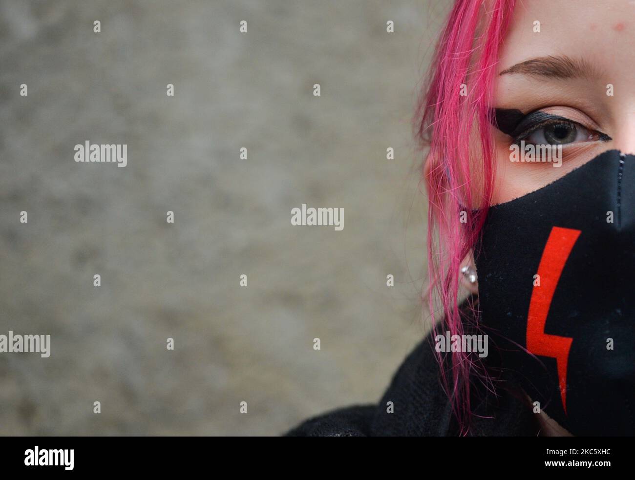An activist wears a face mask with a red lightning bolt during a ...