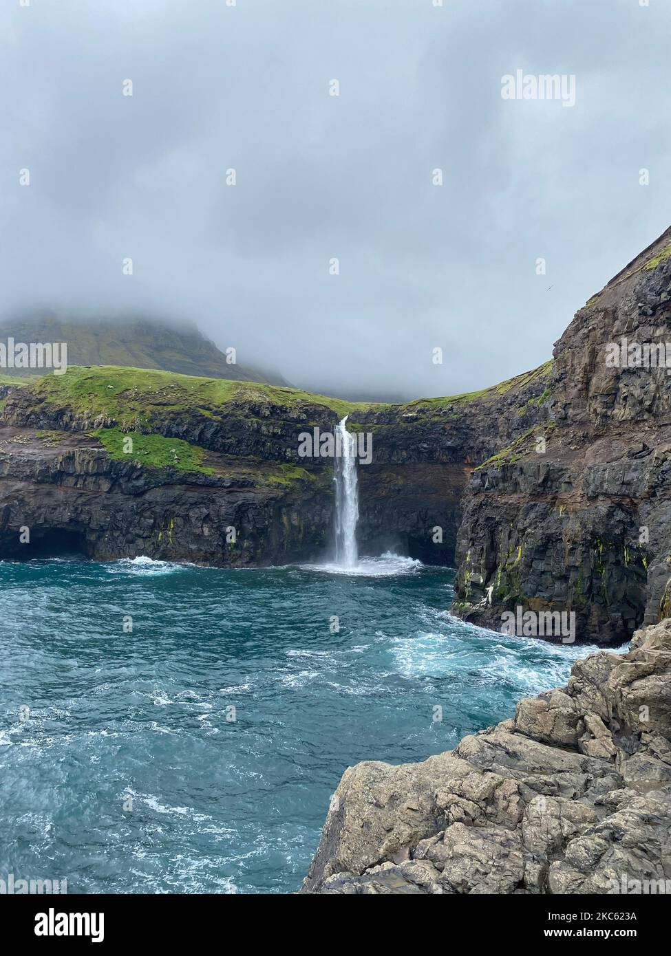 A vertical shot of a waterfall on a cliff in the Faroe Islands Stock ...