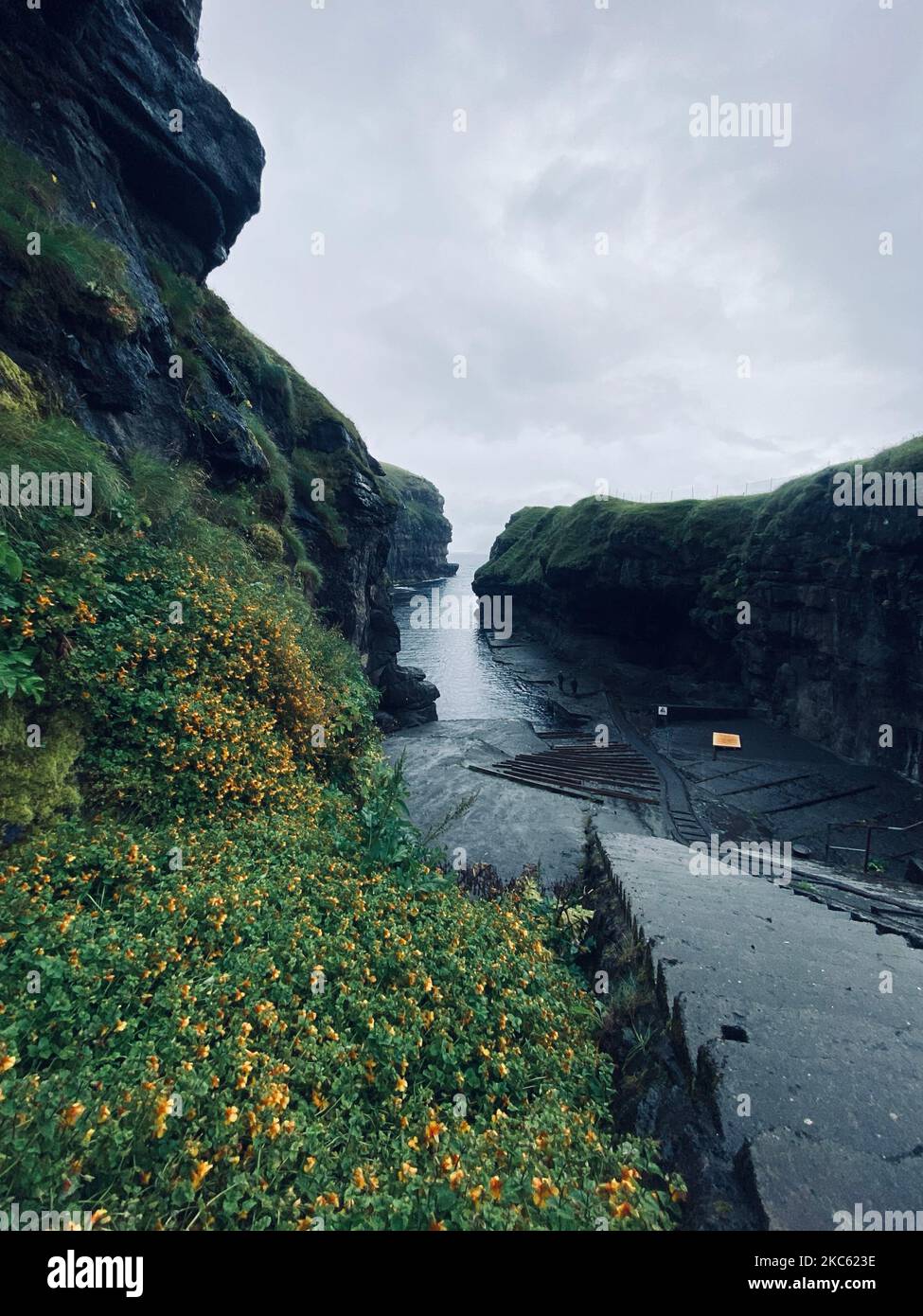 A vertical shot of a river surrounded by cliffs in the Faroe Islands ...