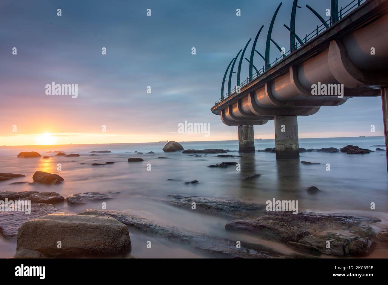 A bridge on the sea with a sunset background Stock Photo - Alamy