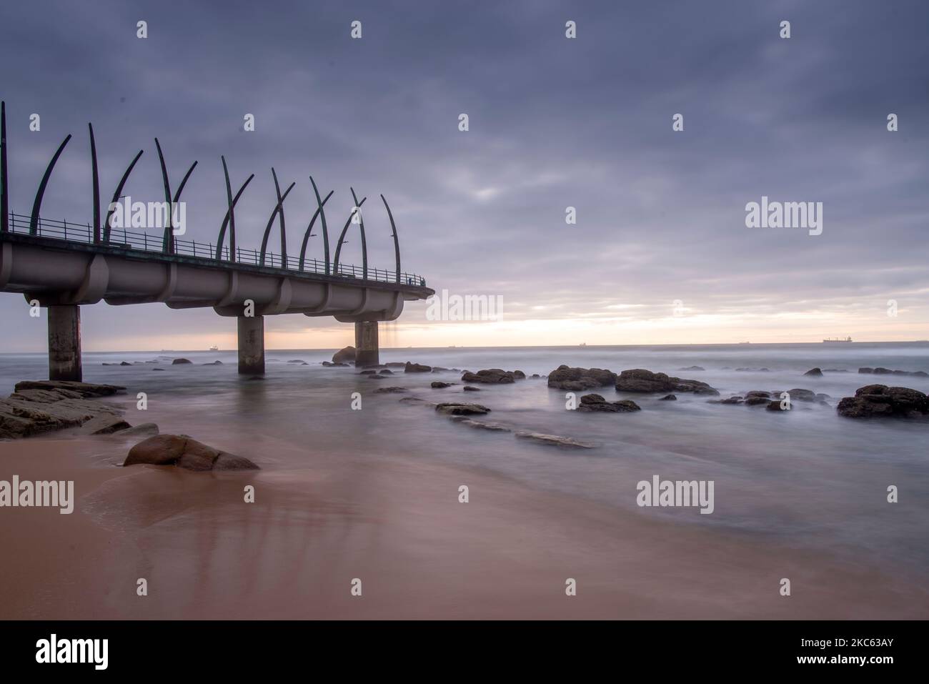 A bridge on the sea with a sunset background Stock Photo - Alamy