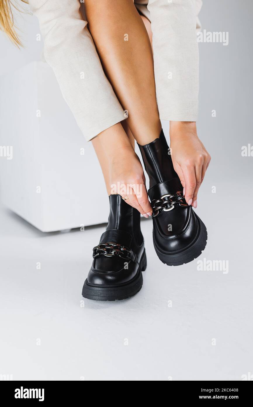 Women's black spring boots made of genuine leather are put on a woman's ...
