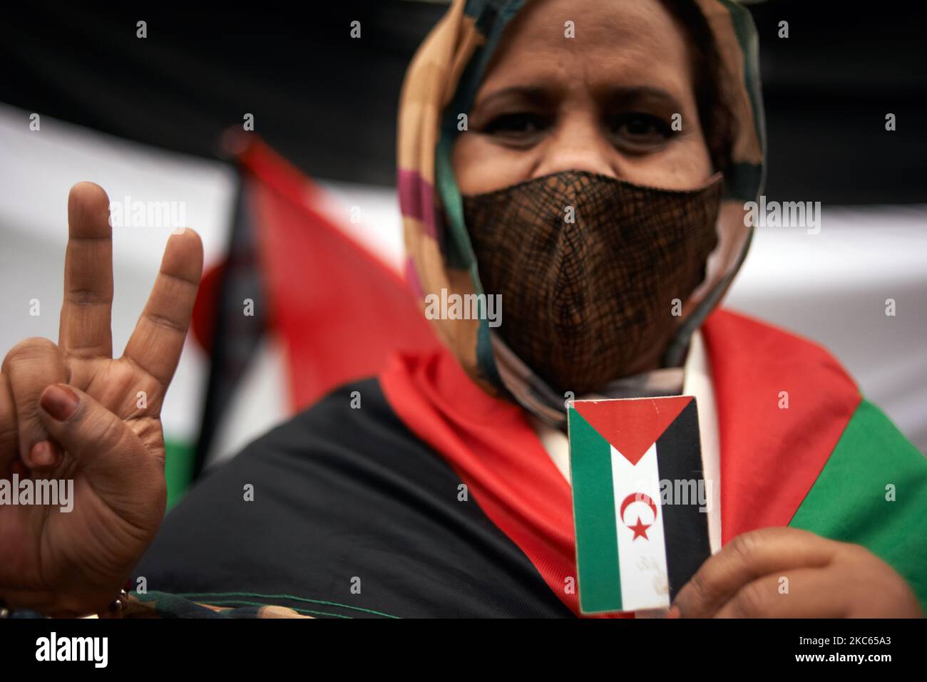 A woman makes the 'V' sign and holds a Sahrawi flag. Sahrawi people of ...
