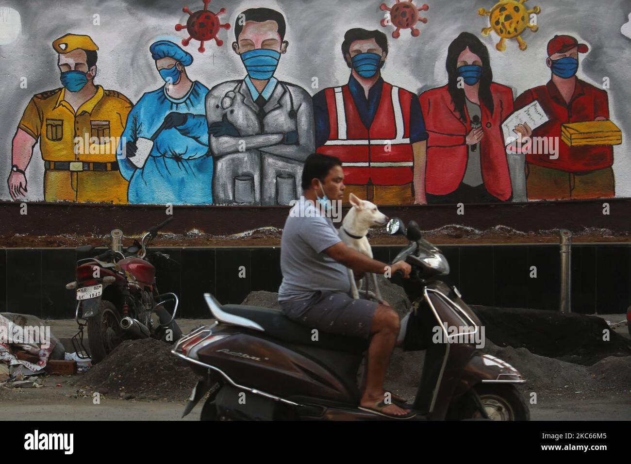A man rides a motorbike with his dog past a mural in tribute to ...