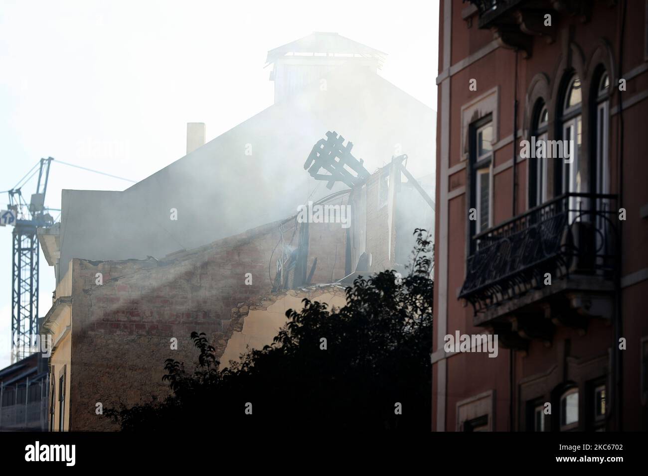 Smoke rises from a destroyed building that collapsed and caught fire ...