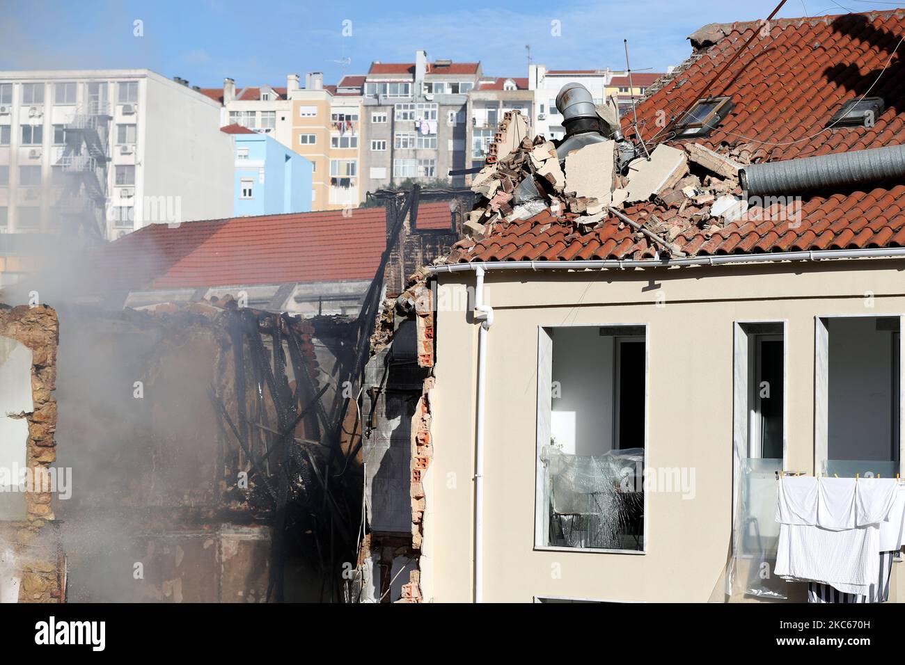 Smoke rises from a destroyed building that collapsed and caught fire ...