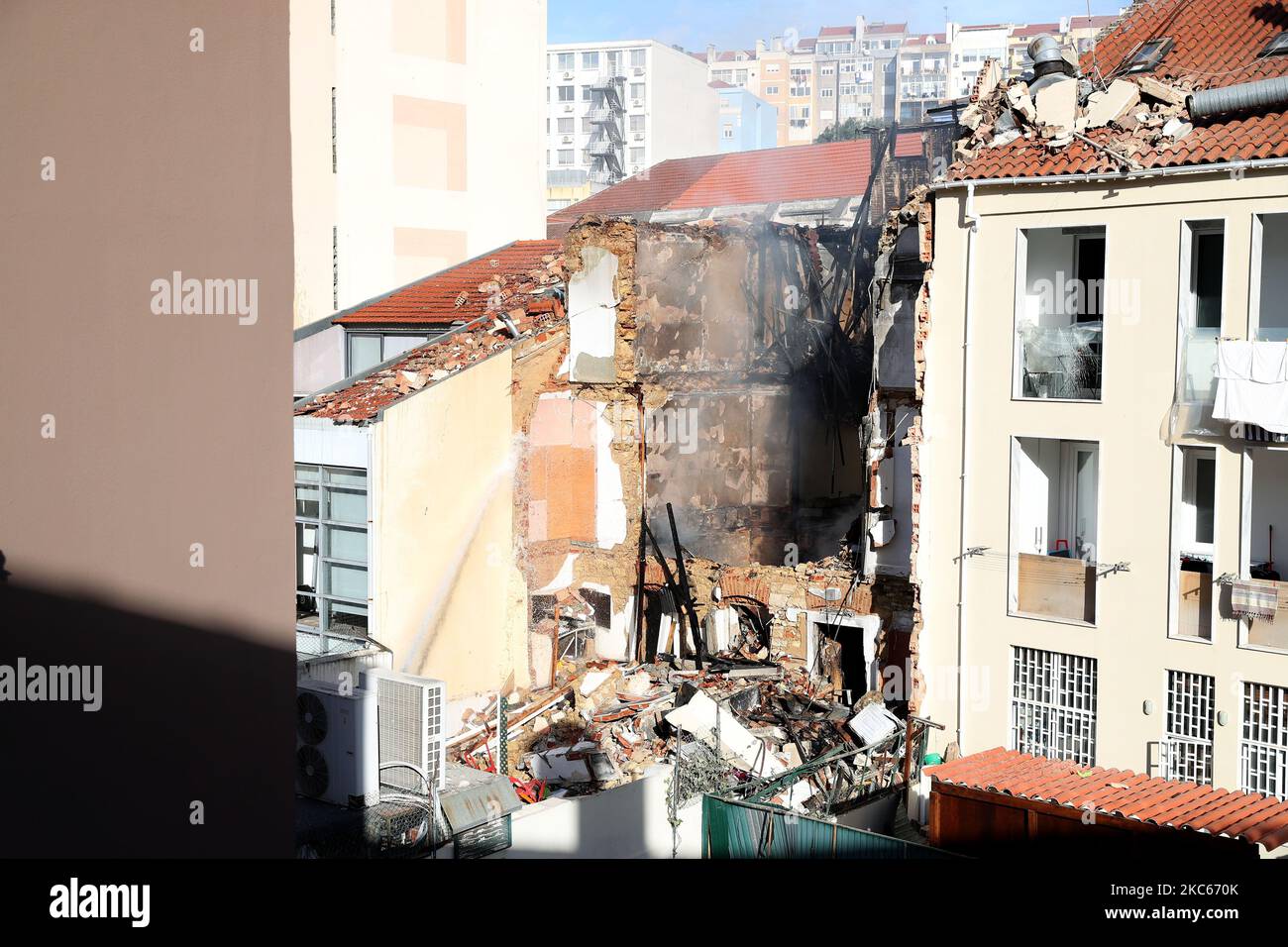 Smoke rises from a destroyed building that collapsed and caught fire ...