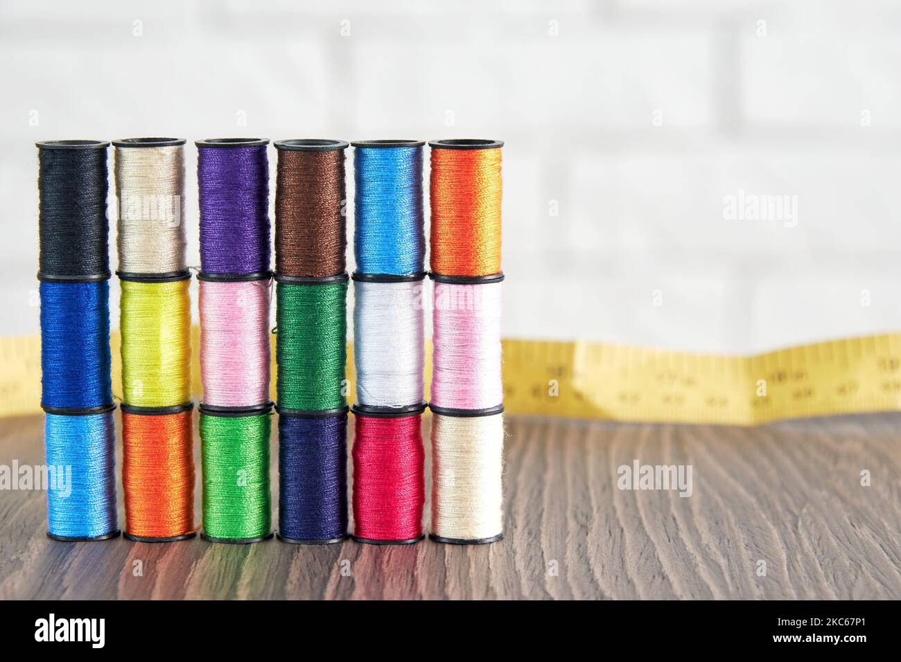 Rows of spools of colorful sewing threads and measuring tape on the ...