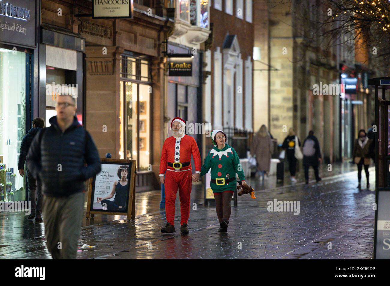 A couple dressed as Santa Claus and an elf on an almost empty King ...