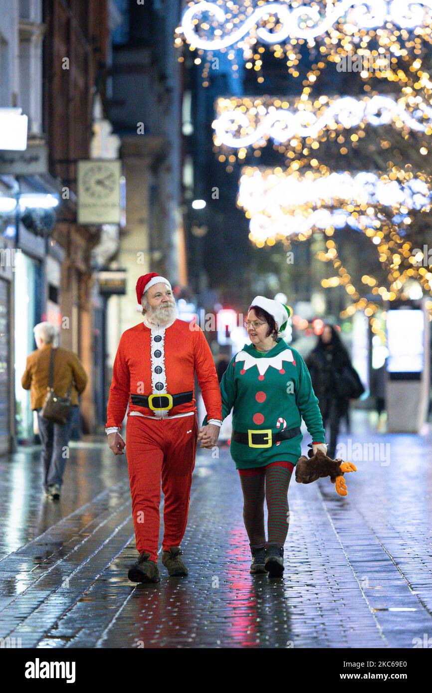 A couple dressed as Santa Claus and an elf on an almost empty King ...